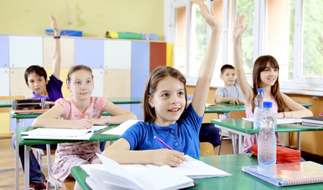 Studenti Della Scuola Elementare Alzano Le Mani In Classe Immagini